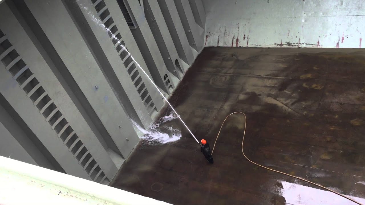 Ship crew cleaning lower areas of cargo holds using high pressure ...