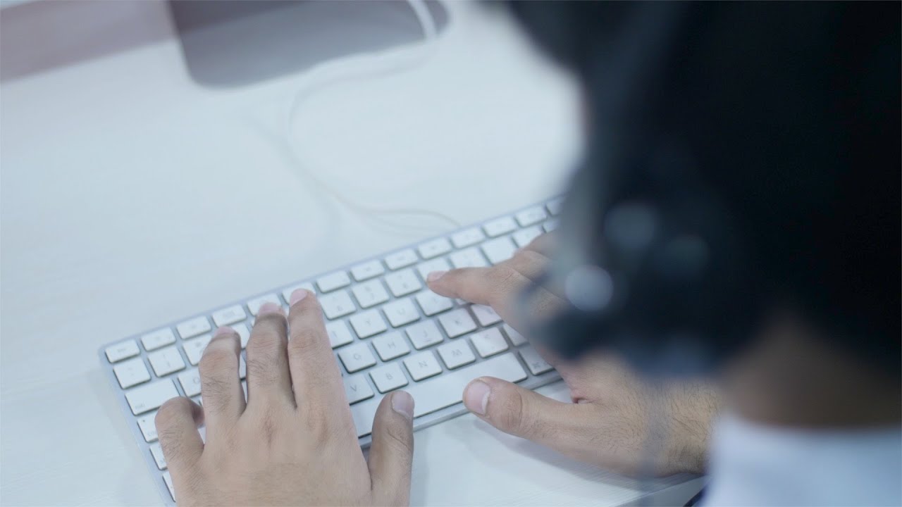 An Indian call center employee with headphones typing on a key ...