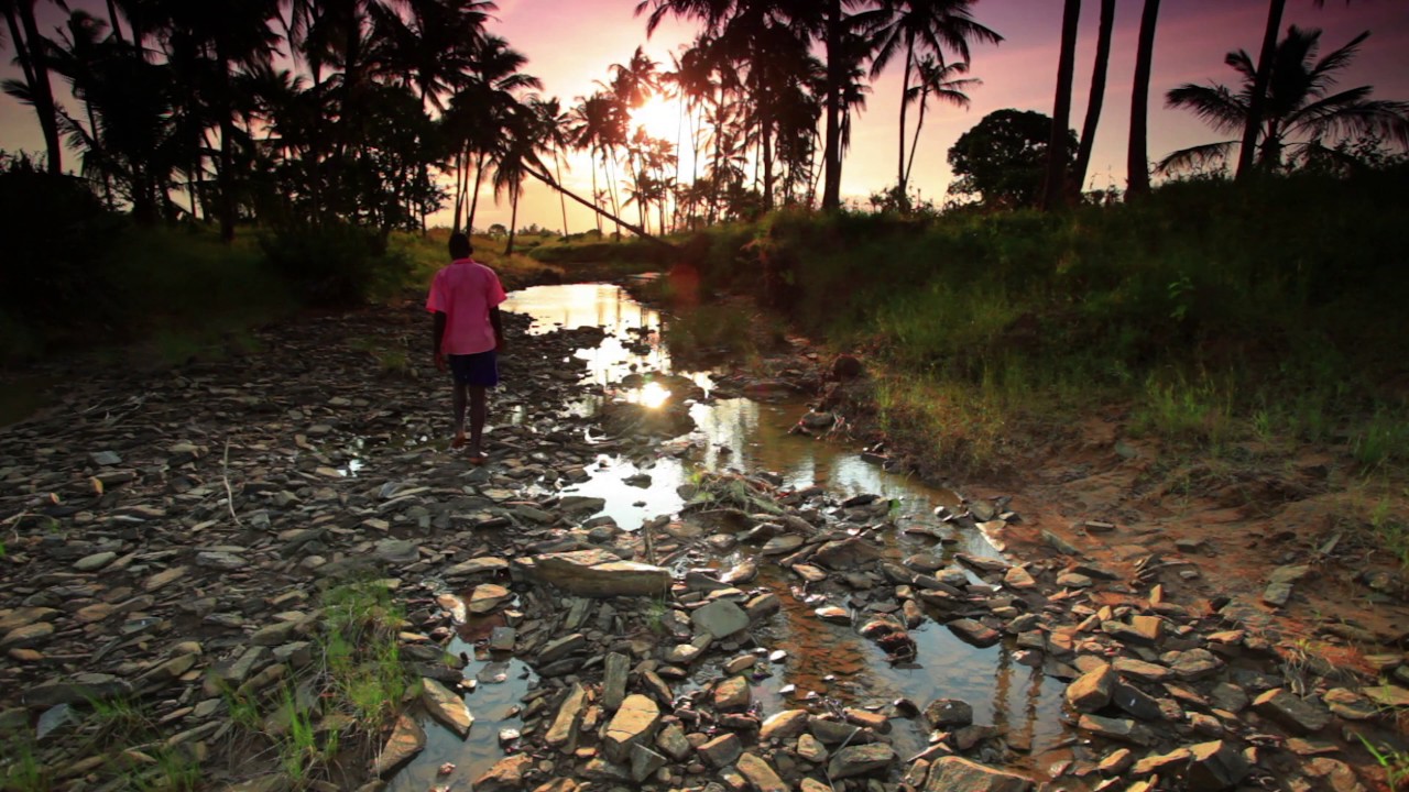 Boy walking along a rocky stream in Africa at sunset. - YouTube