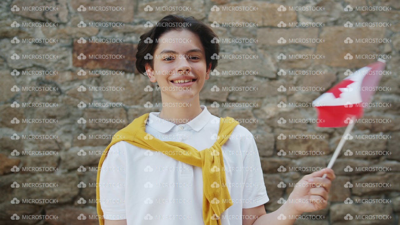 Portrait of teenage boy waving Canadian flag standing outdoors smiling ...
