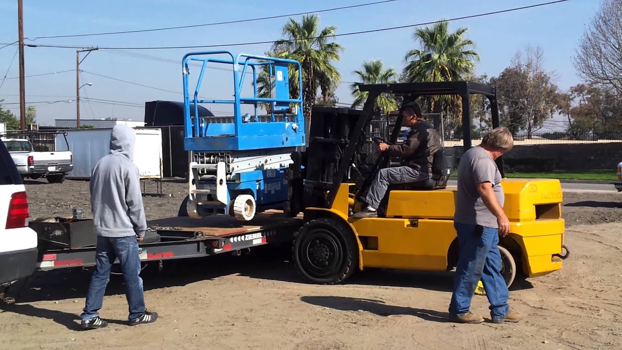 Forklift Unloading a Scissor Lift from a Trailer - YouTube