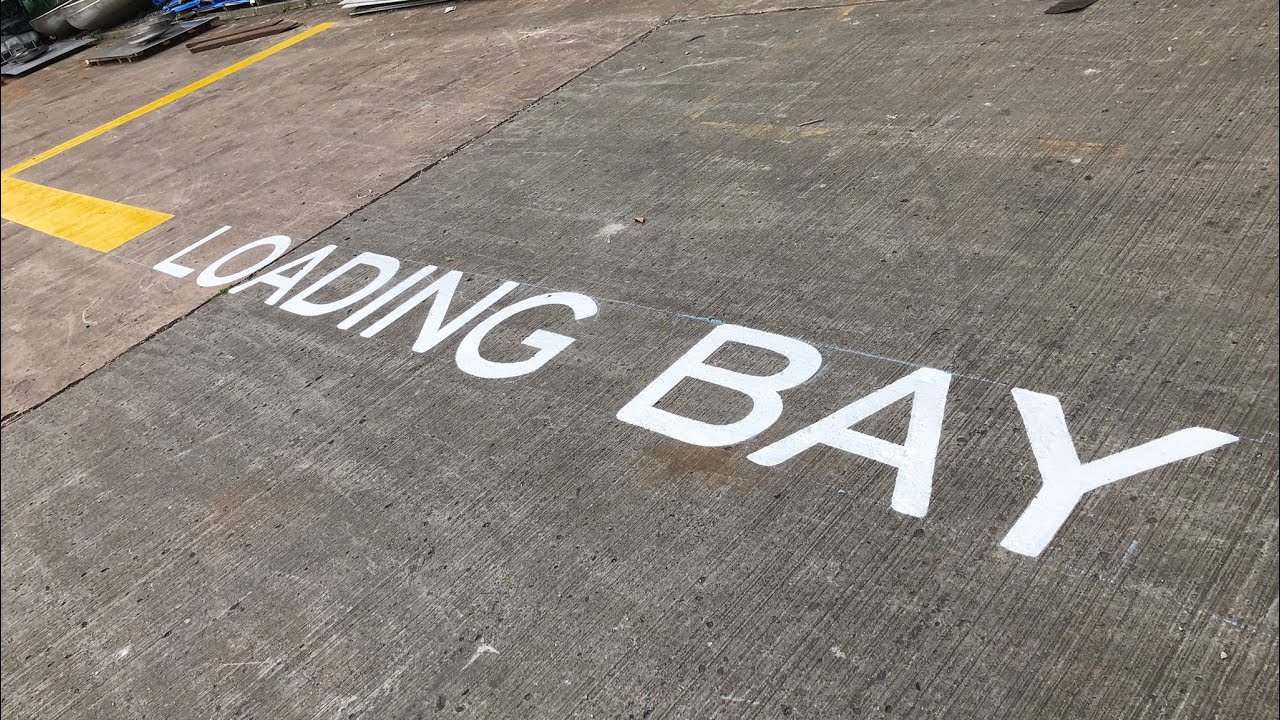Hand painting Road marking lettering for Loading Bay with a paint brush ...