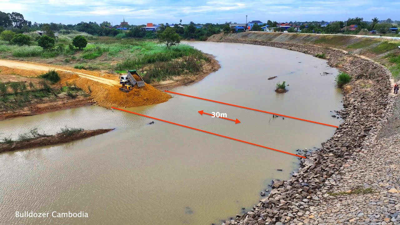 Caterpillar Komatsu dozer pushes the ground into the water creates a ...