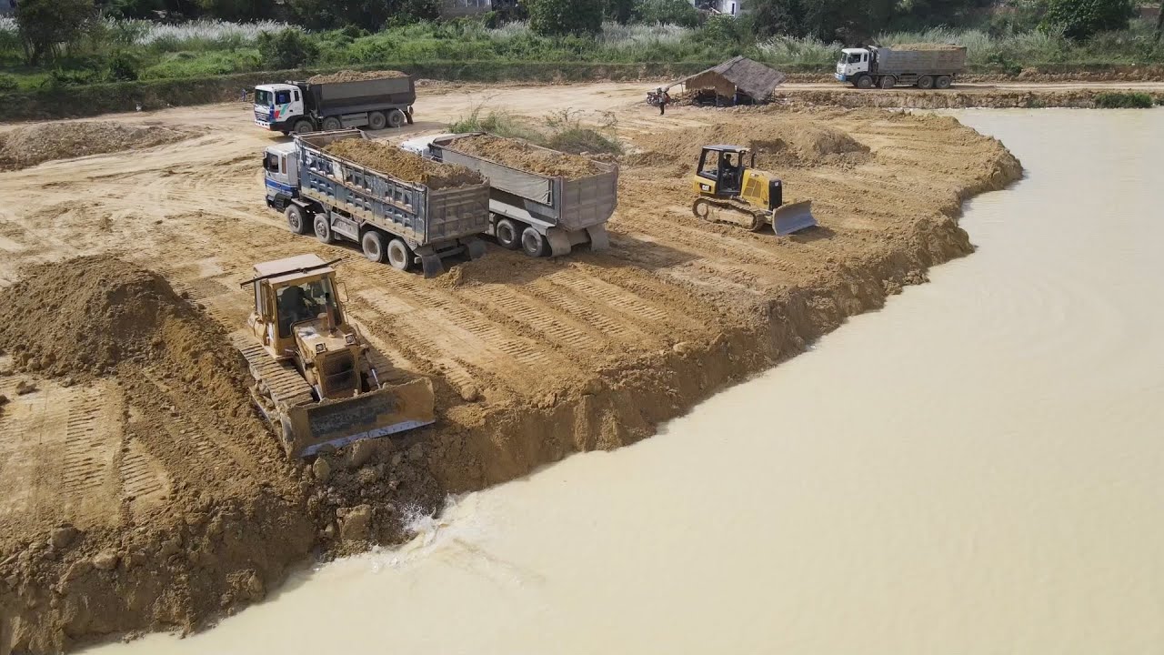 Expertly Mini Cat and Komatsu Dozers Pushing Soil into water ...