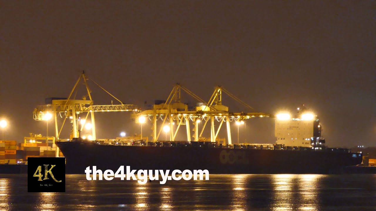 4K UHD - Huge cargo ship at night with cranes lifting containers in ...