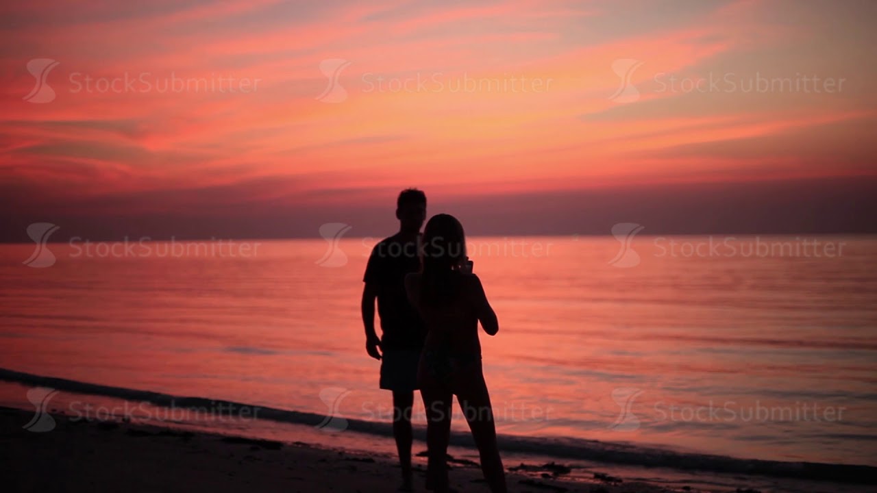 Silhouette of couple taking photo on beach during amazing sunset. hd ...