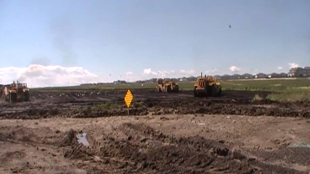 Caterpillar scrapers stripping topsoil - YouTube