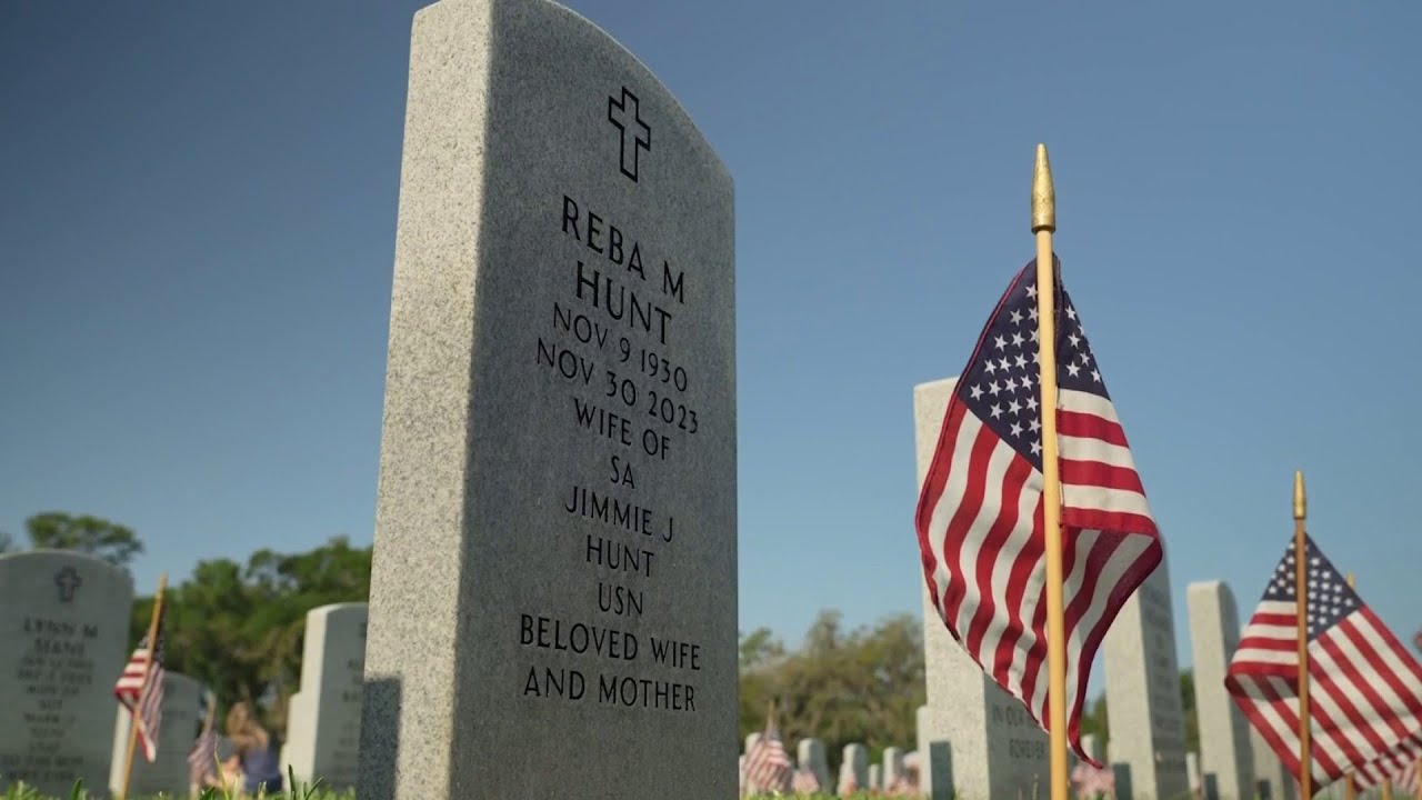 Volunteers place American flags at grave sites at the Florida National ...