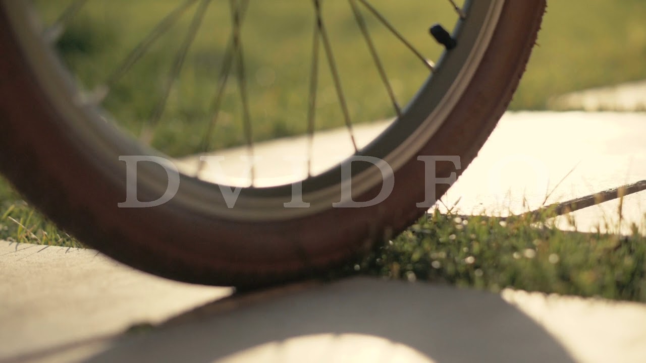 Bicycle wheels moving on green grass close up. Legs walking beside ...