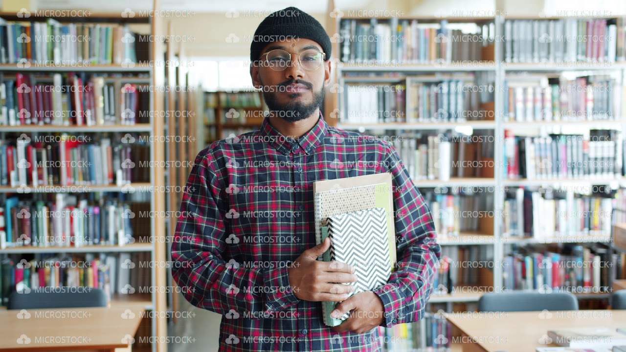 Portrait of serious African American student holding books in ...
