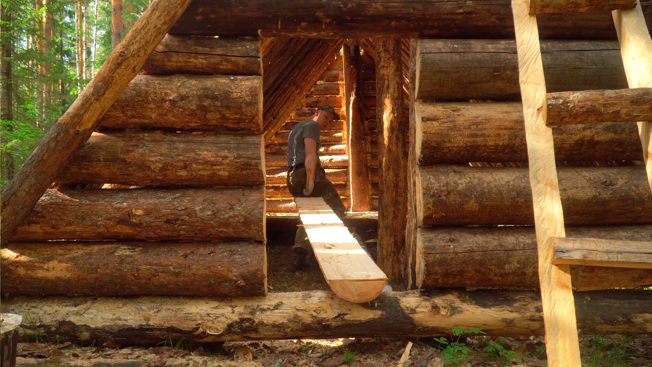 A MAN BUILDS A LARGE LOG CABIN ALONE. THE FLOOR IS MADE OF PINE BOARDS ...