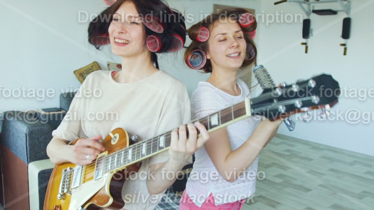 Slow motion of two funny girls singing with comb and playing electric ...