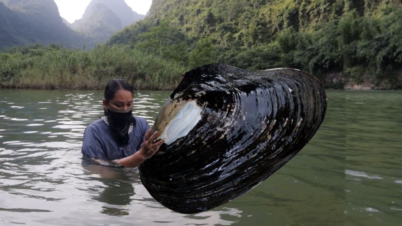 The girl sneaked into the bottom of the river and picked up a clam ...