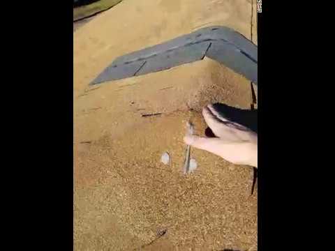 Installing the final cap shingle at a hip and ridge junction. - YouTube