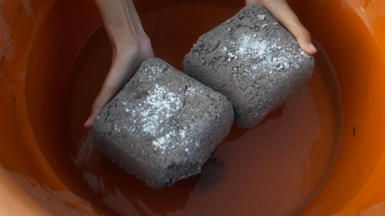 New white powder pouring on cement shapes crumbling in lot's of water ...