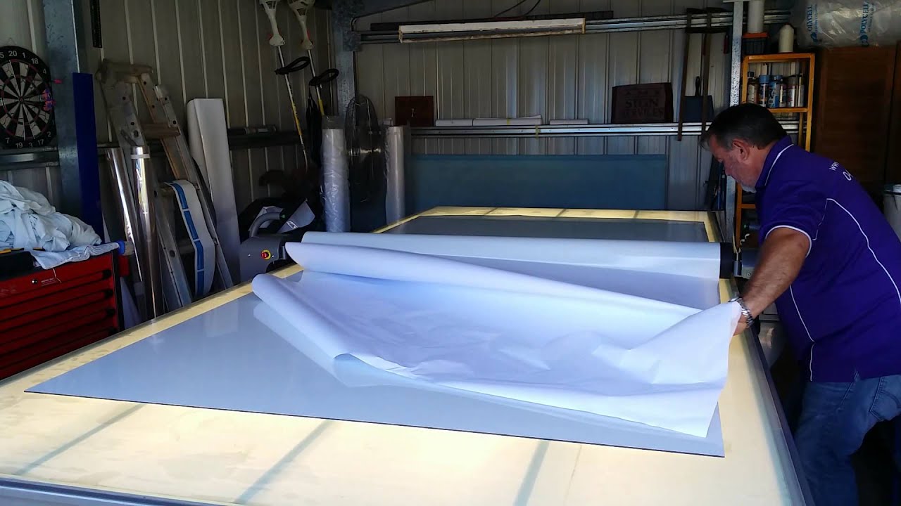 Andrew from AMS Signs applying 3000x1500 laminate sign to panel - YouTube