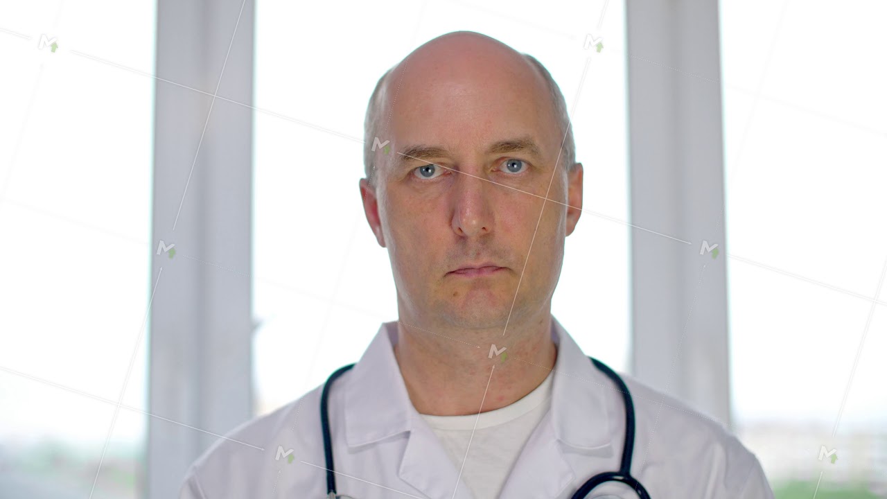 Serious male doctor swaying head and talking yes on window background ...