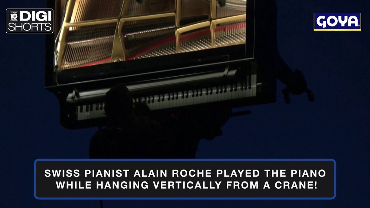 Swiss man plays piano while hanging vertically from crane - YouTube