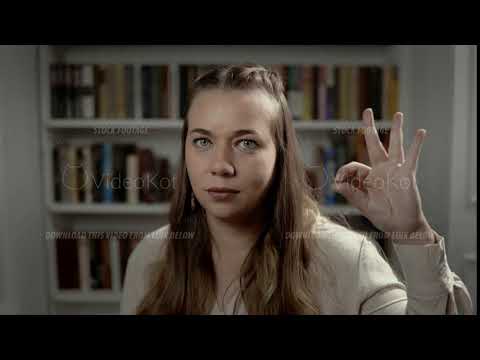 Young woman is watching straight in the camera and showing ok sign