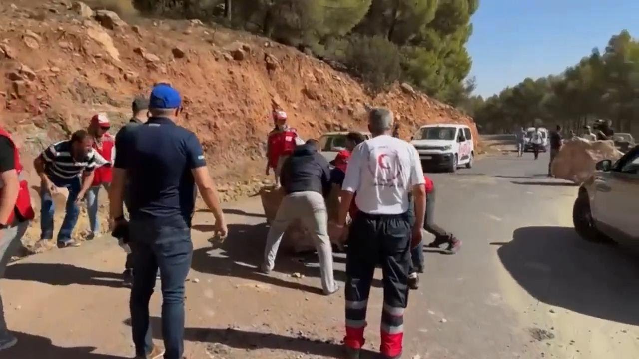 People try to move boulder blocking road after powerful earthquake ...