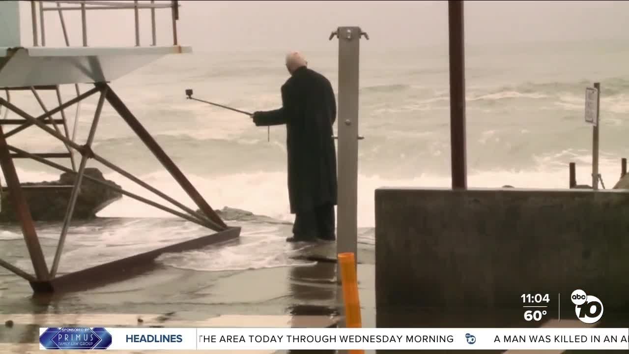'Oceanside trenchcoat guy' takes on rain and waves as storm hits North ...