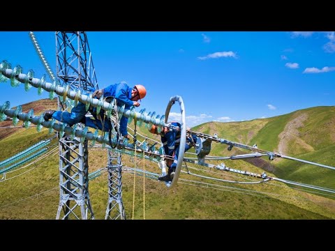 High Voltage Line construction | Men on wire: Power workers walk in the ...