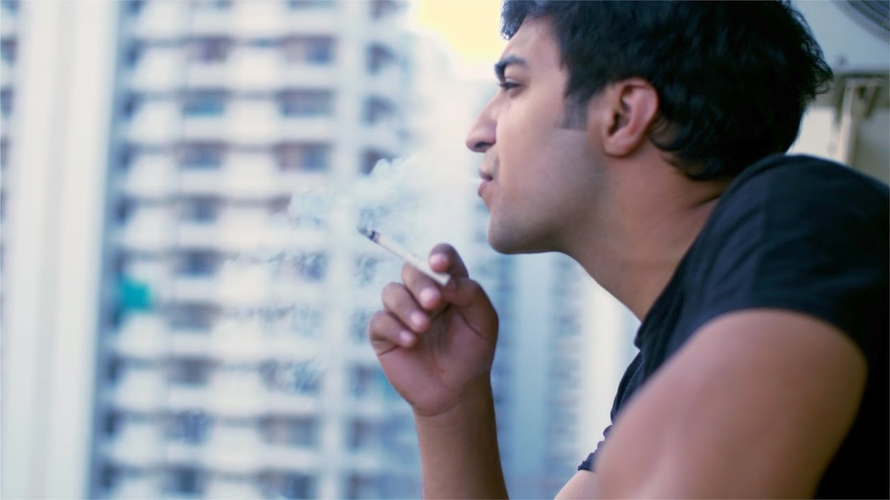 Young Indian man smoking a cigarette in the balcony | Indian Stock ...