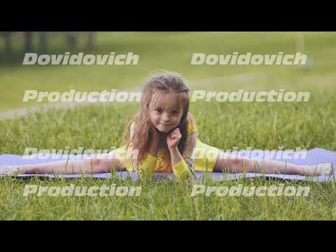 The little girl performs an element of rhythmic gymnastics - splits in the park.