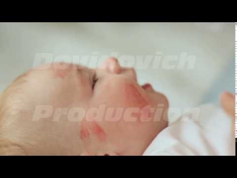 Mum kisses the baby and leave a bright trace of lipstick kiss
