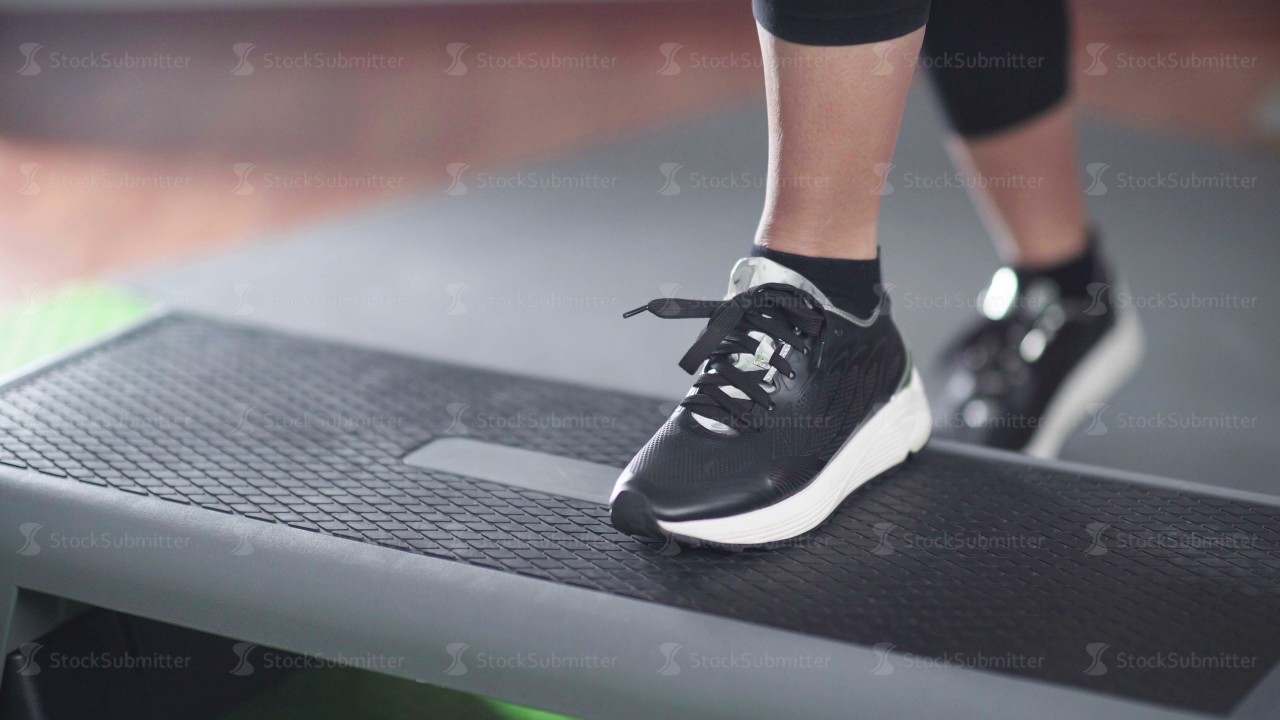 Close-up of female black athletic shoes stepping on a step platform ...