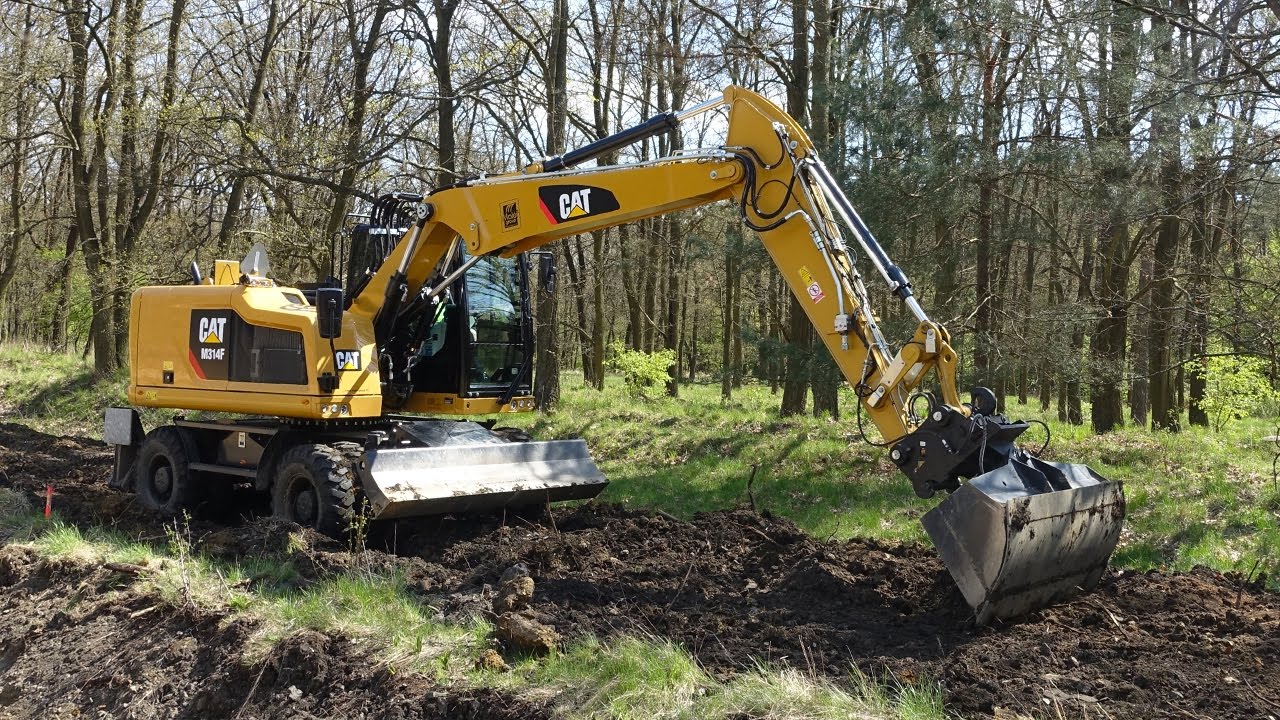 New CAT M314F wheeled excavator grading clay - YouTube