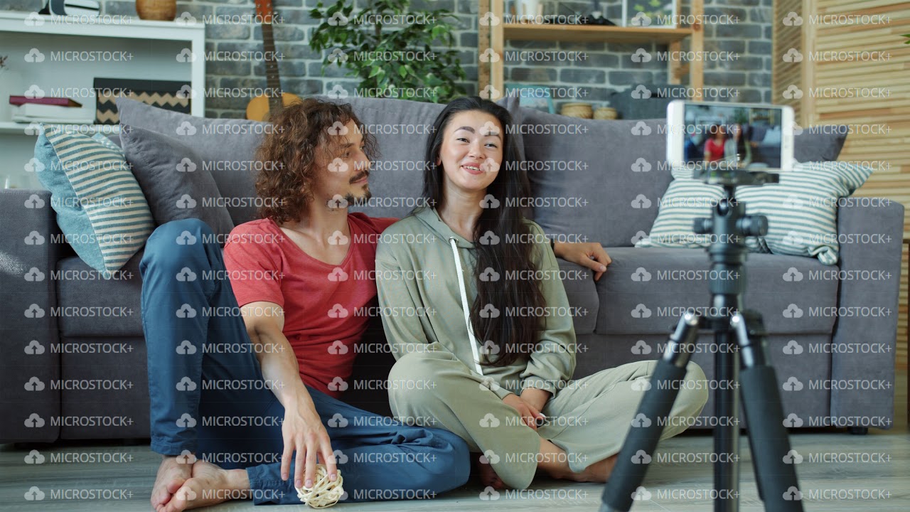 Young couple recording video for internet vlog in apartment using ...