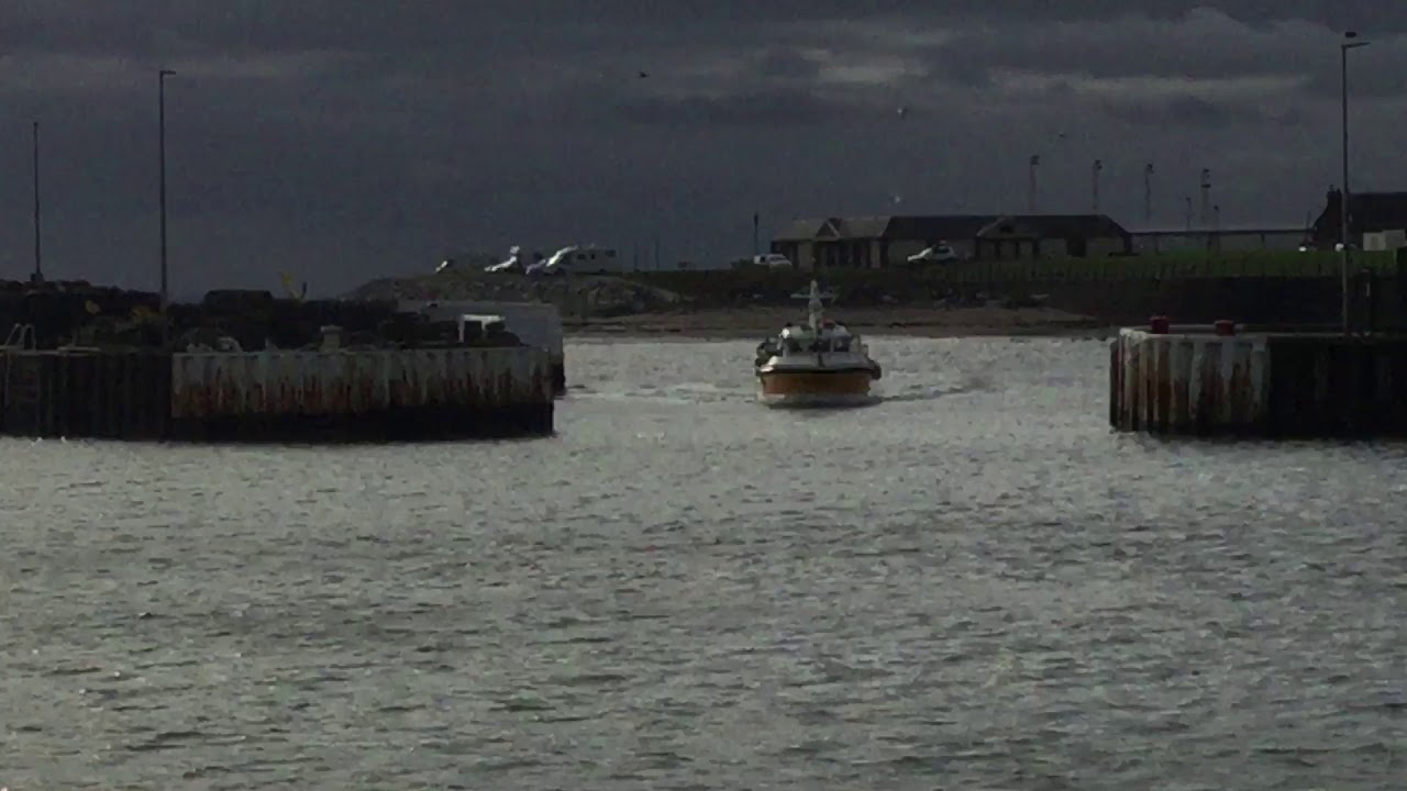 A yellow fishing boat named Maverick arriving at Arbroath Harbour ...