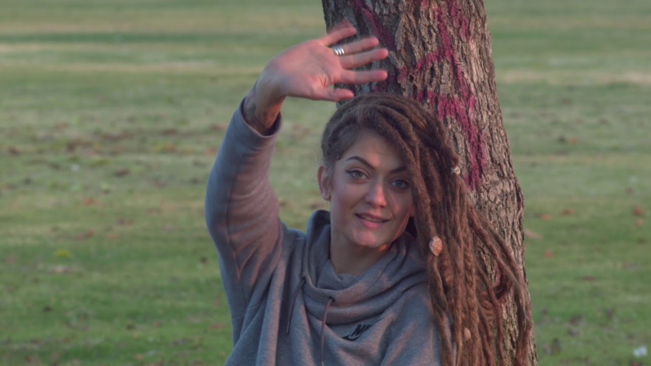 Smiling young white rasta girl withdreadlock sitting in a cold public ...