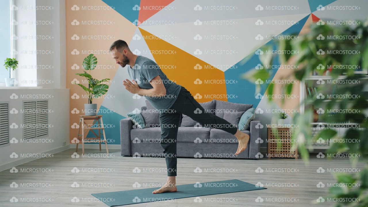 Slow motion of handsome man balancing on one leg doing yoga in ...