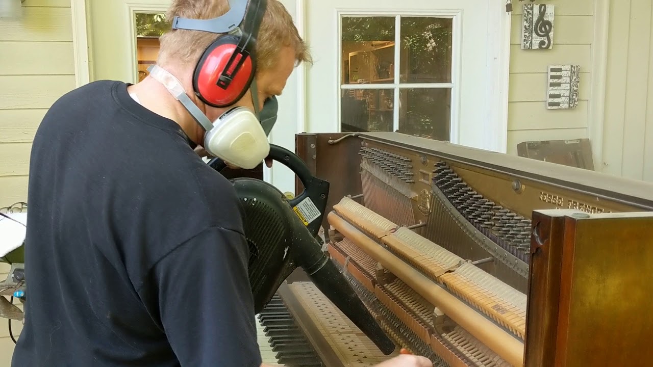 Blowing dust out of an upright piano before moving it inside. - YouTube