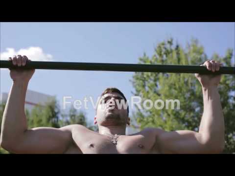 Front view. Man with naked chest is pulling up outdoors