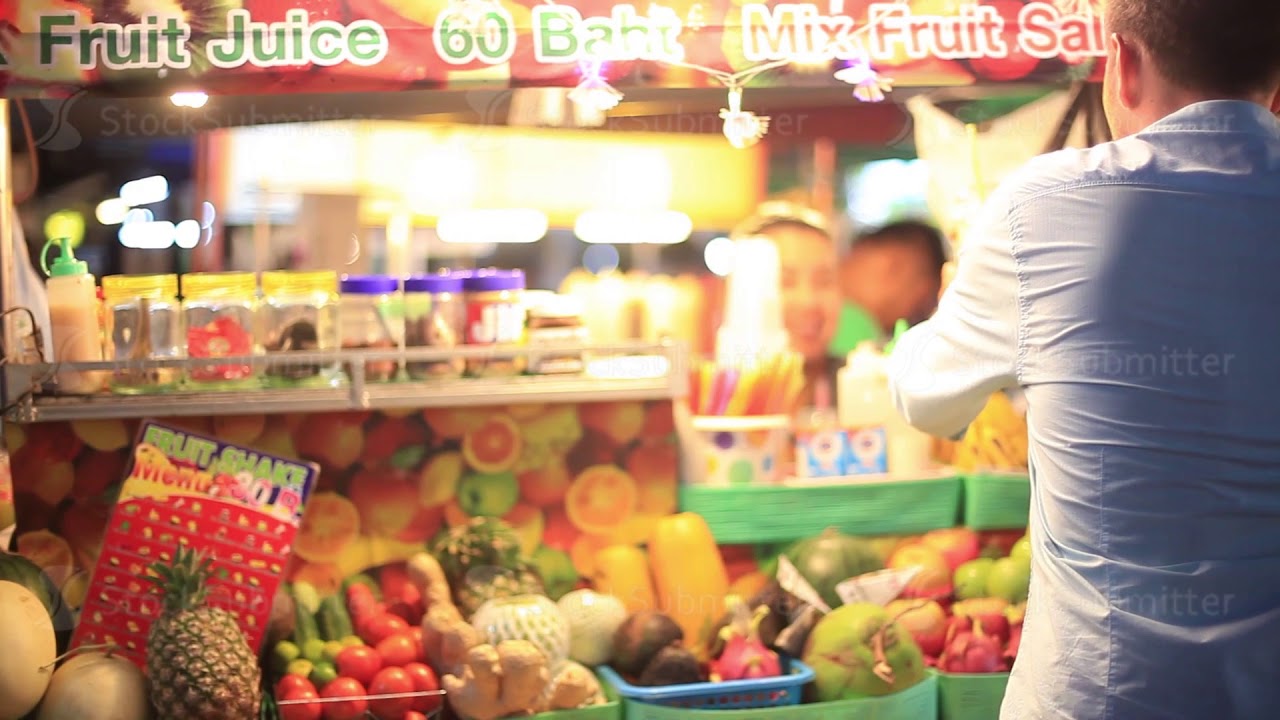 Fresh fruit cocktails on Asian street markets. Young man buys a fruit ...