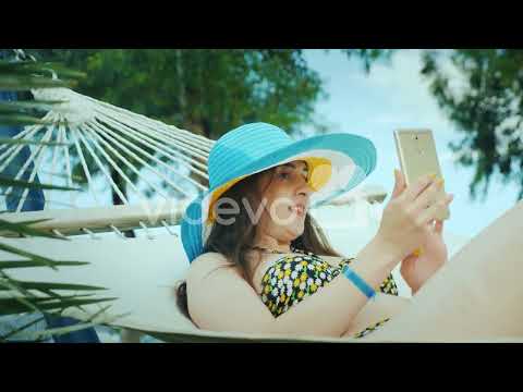 A Cute Brunette In A Wide Brimmed Hat And In A Bikini Enjoys Relaxing In The Seaside Resort Reading