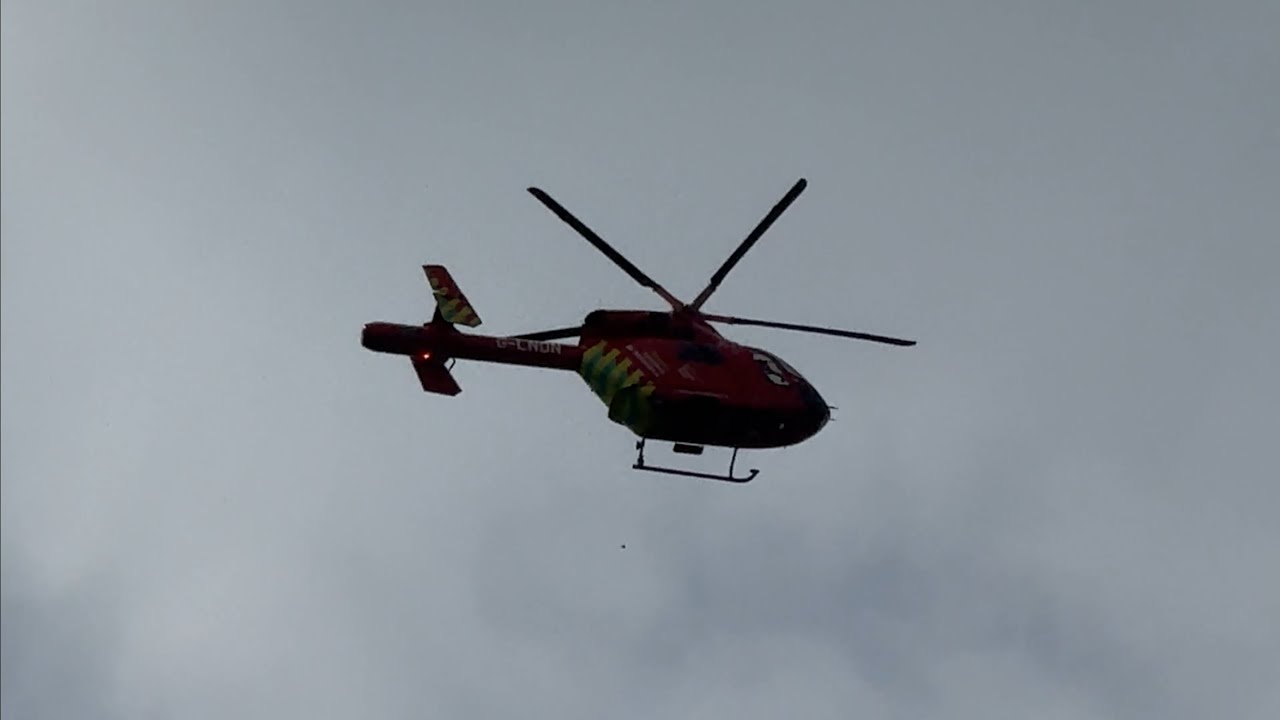 London Air Ambulance MD900 Explorer cutting past the trees with her all ...