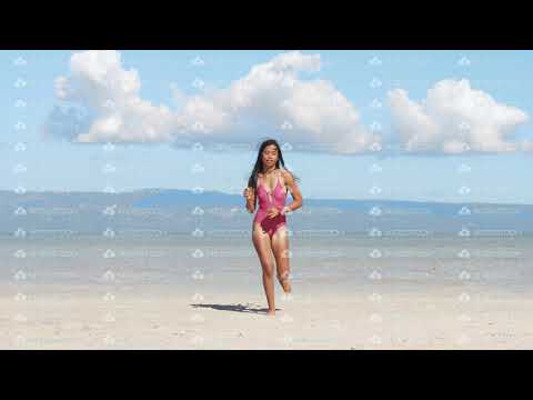 Pretty asian girl jogging in swimsuit on sand ocean tropical island, front view.