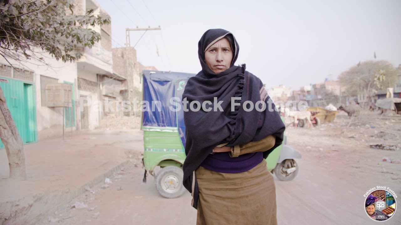 Old Female rickshaw driver walks towards the camera and cross her hands ...