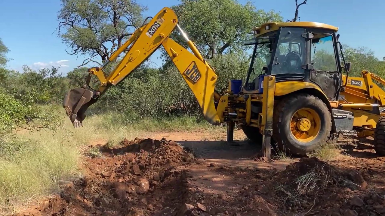 Road works in African Game Reserve - digging a drain with a TLB - YouTube
