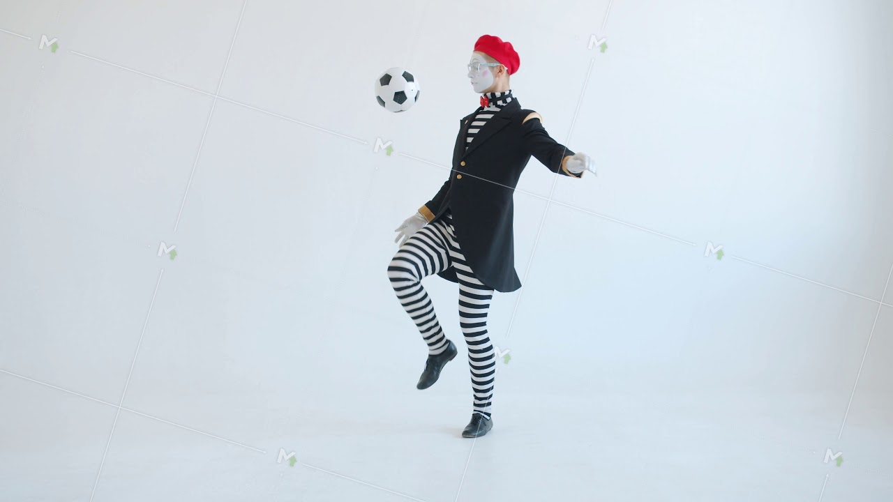 Mime artist in bright clothing playing with ball looking at camera on ...