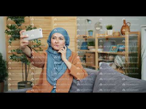 Attractive Muslim girl in hijab taking selfie with smartphone camera at home