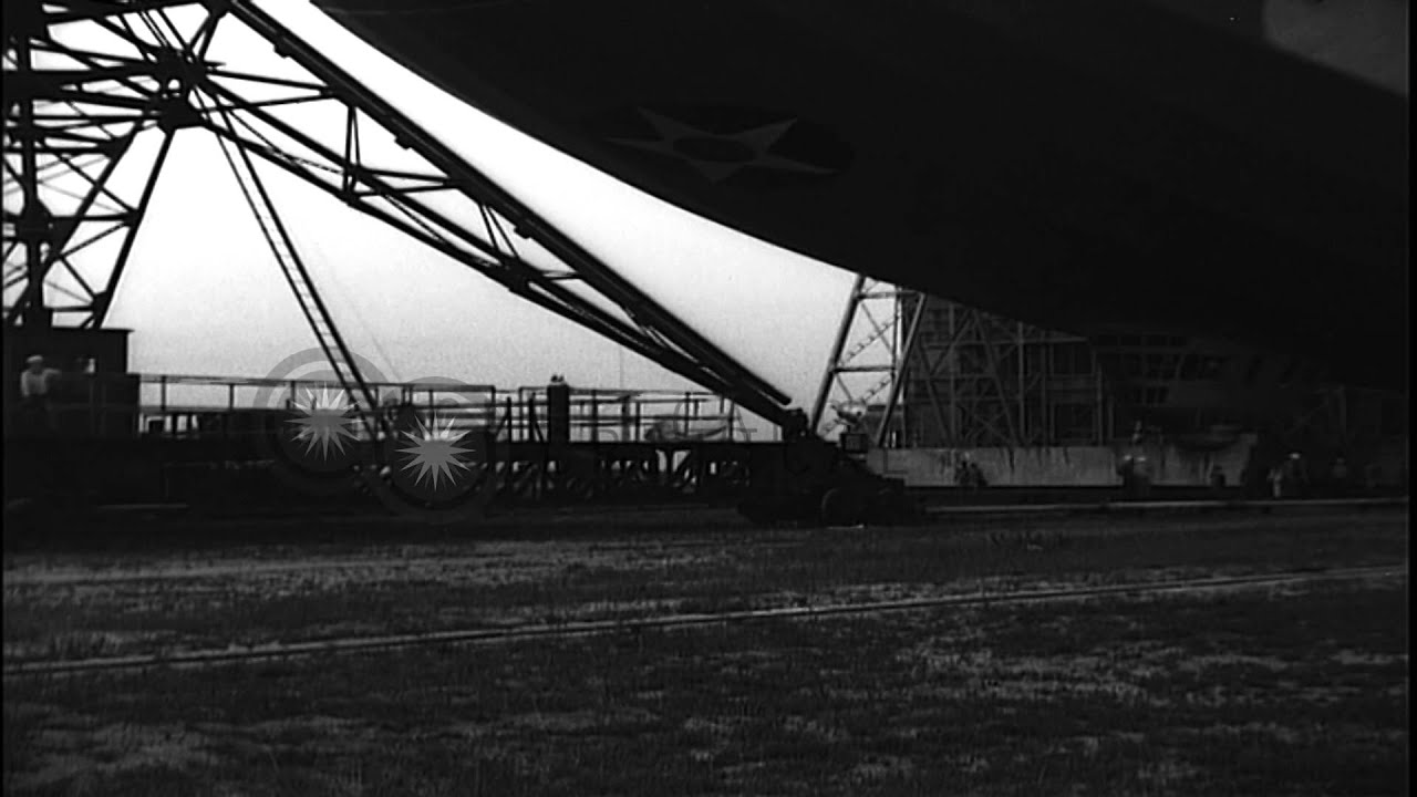 Ground crew move the airship USS Akron on mooring masts out of its ...