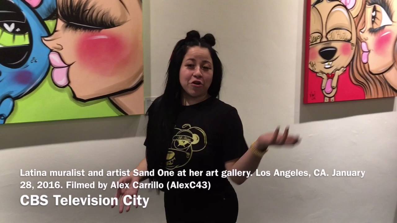 Latina muralist and artist Sand One speaking at her art gallery ...