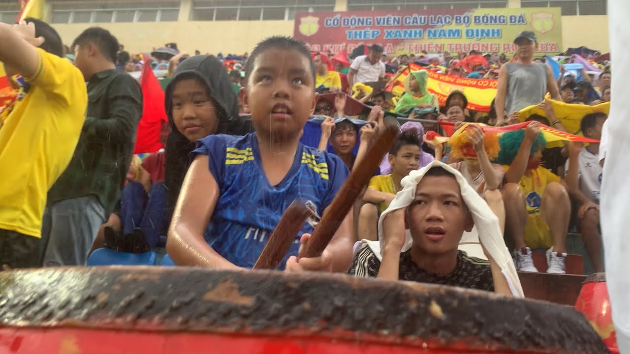 Cổ động viên nam định nhỏ tuổi đội mưa đánh trống cổ vũ cho thép xanh ...