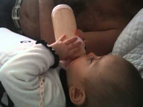 Luiza segurando a mamadeira sozinha