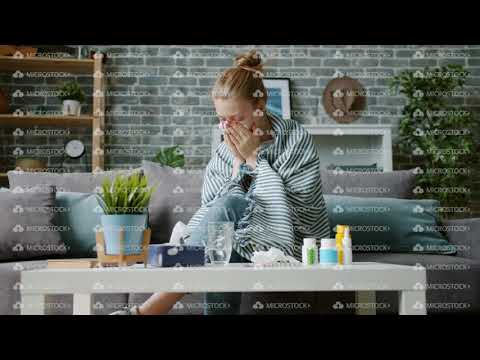 Young woman coughing in paper tissue wiping nose feeling sick at home